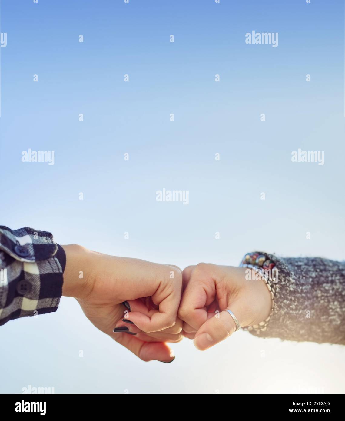 Women, hands and fist bump with blue sky background for friendship ...