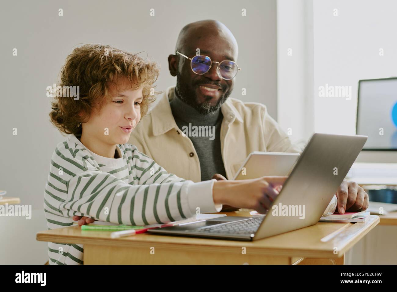 Child smiling and engaging with laptop alongside an adult in cozy ...