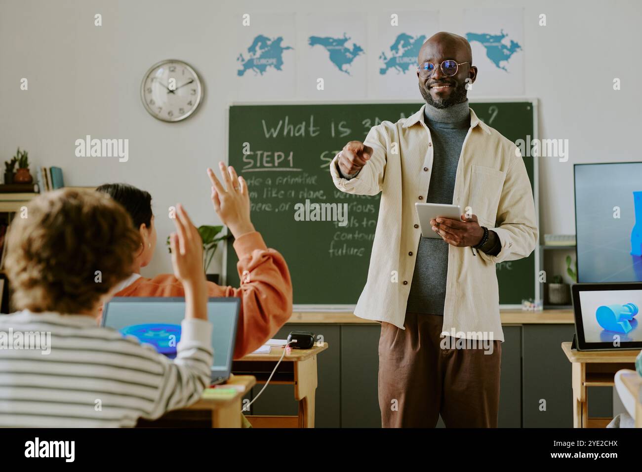 Teacher standing in front of classroom engaging with students while ...