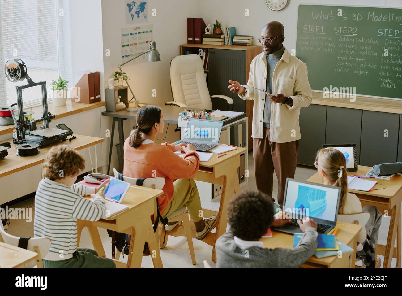 Teacher instructing students about 3D modeling on computers in ...