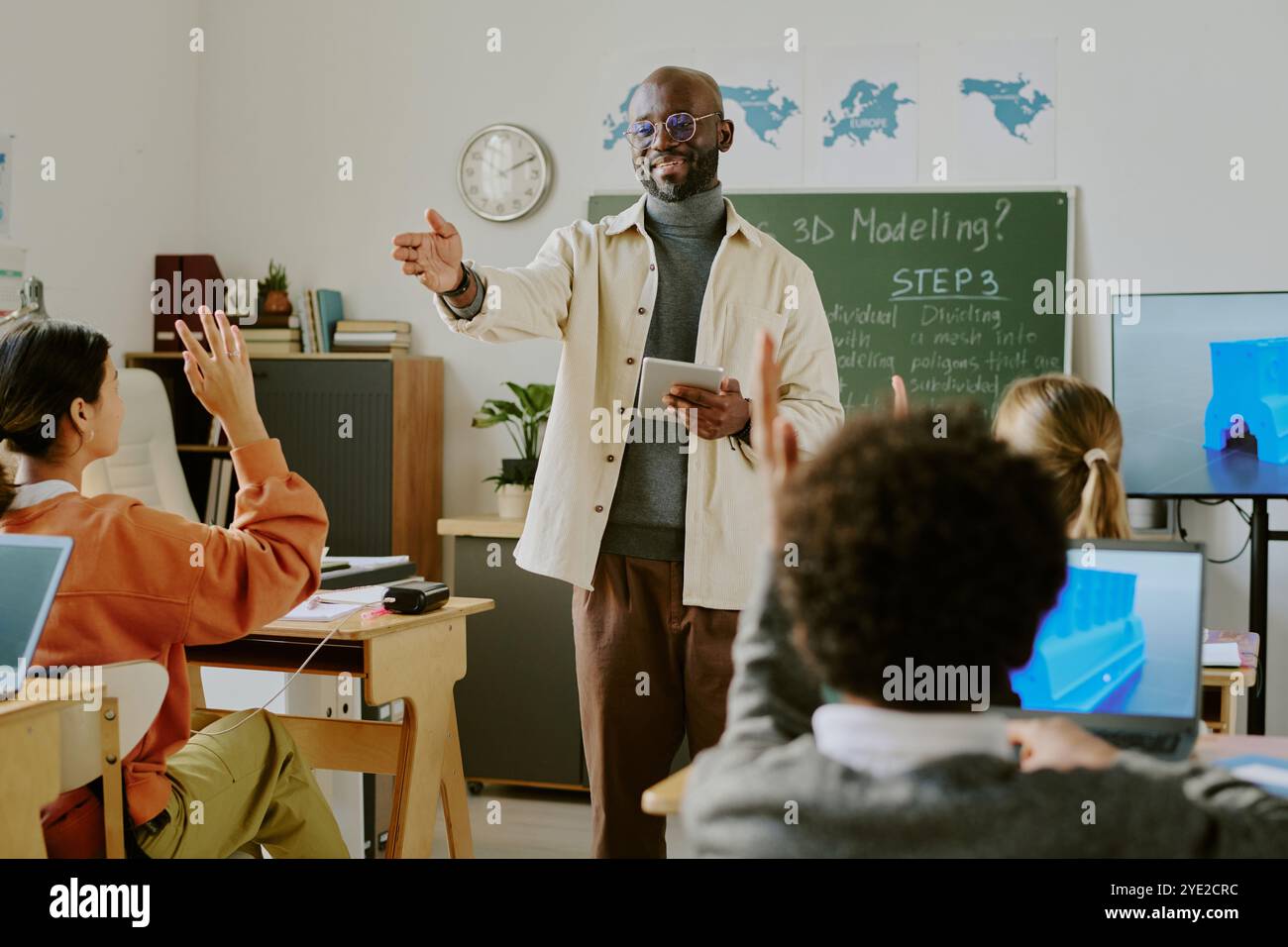 Educator pointing towards students while taking questions in classroom ...
