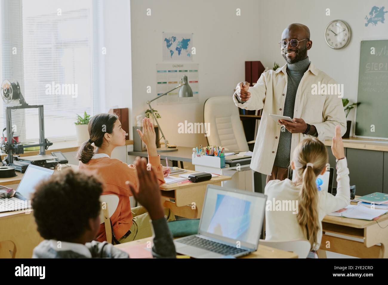 Educator explaining a concept in bright classroom while students ...