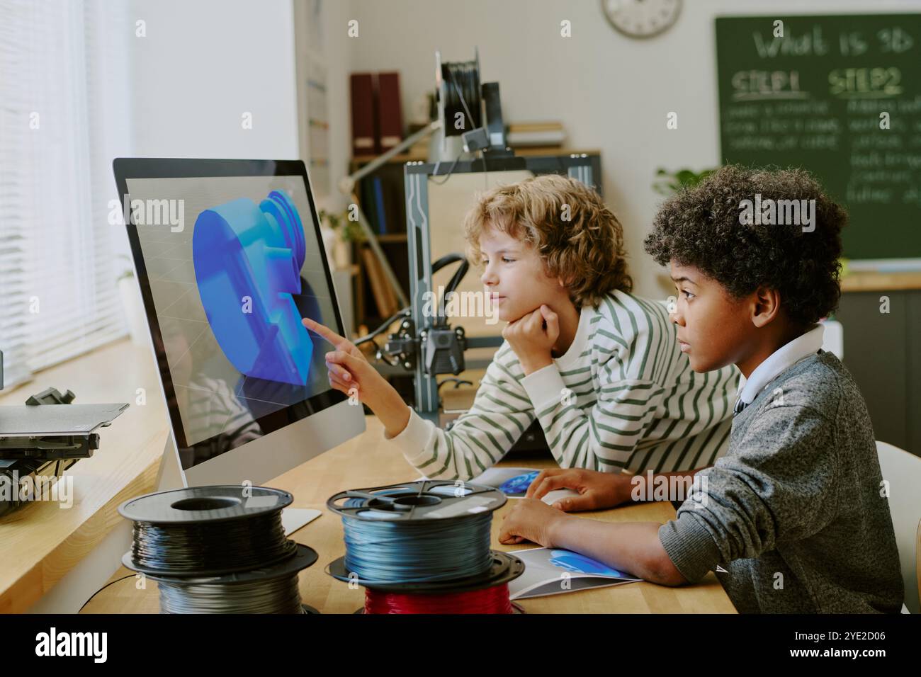 Children focusing on computer screen displaying 3D model in classroom ...