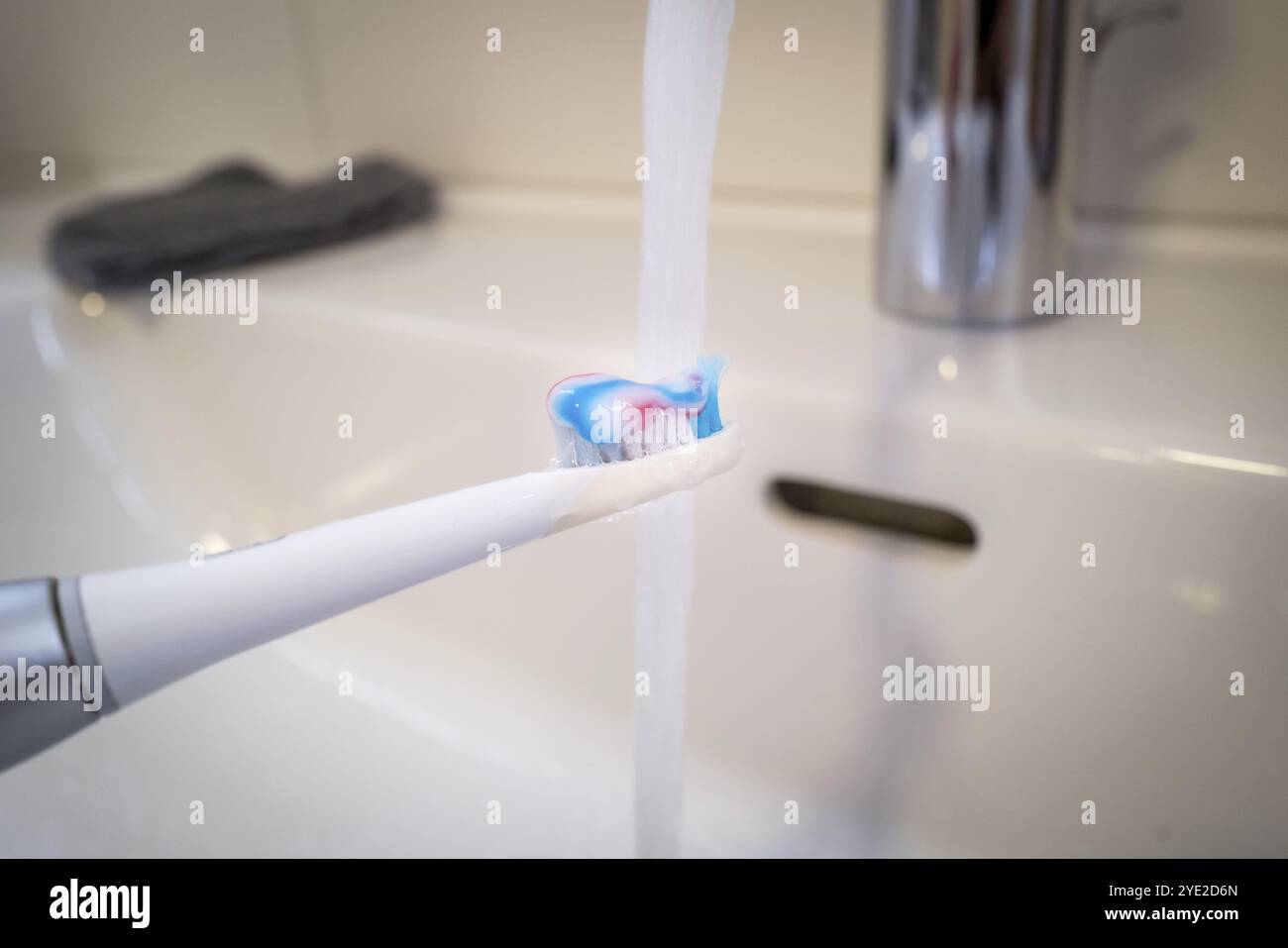 A bathroom tap is running while a toothbrush is held under the running ...