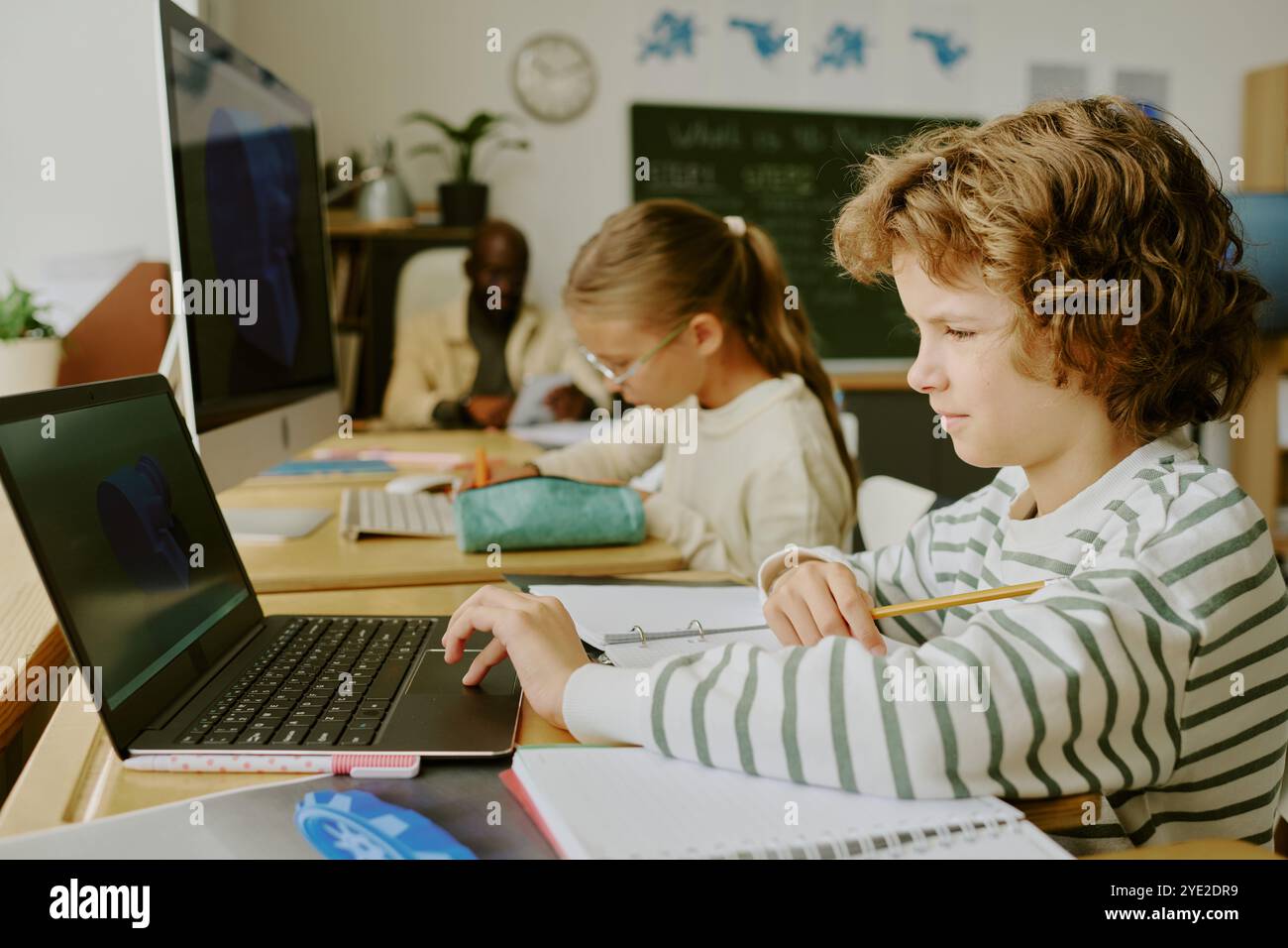 Group of children engaging in study at table, with laptops and ...