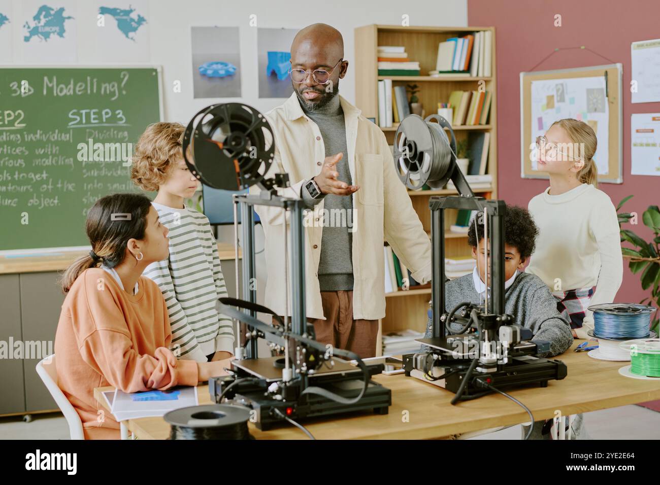 Teacher discussing 3D printing process with attentive students in ...