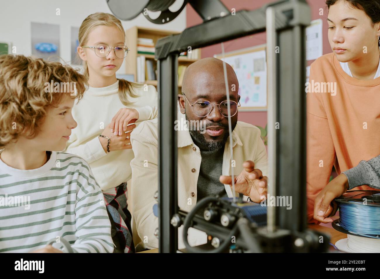 Multiracial group of students and teacher working on project in classroom. Teacher guiding ...