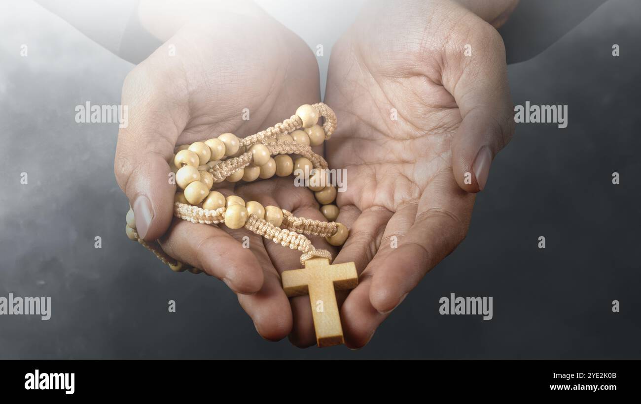 Man holding a rosary beads with dark sky background. Symbol of faith and worship in God. People ...