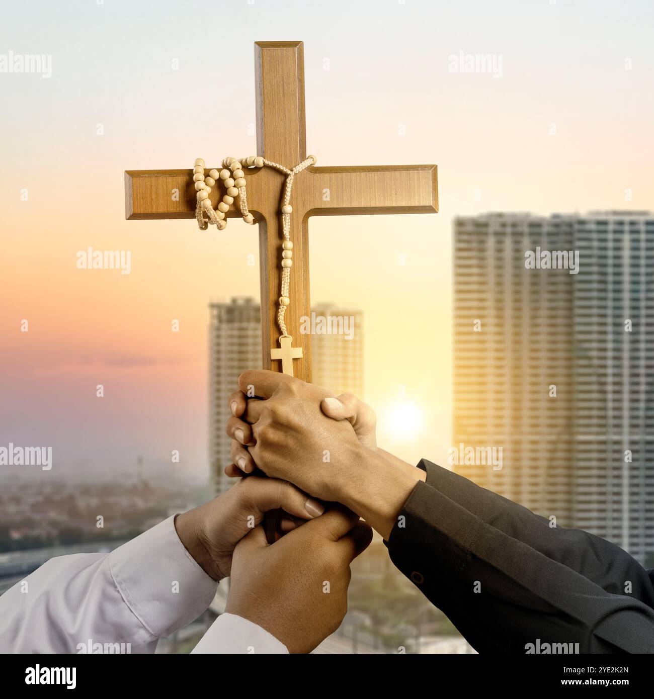 Man holding a religion cross with rosary beads together with sunlight ...