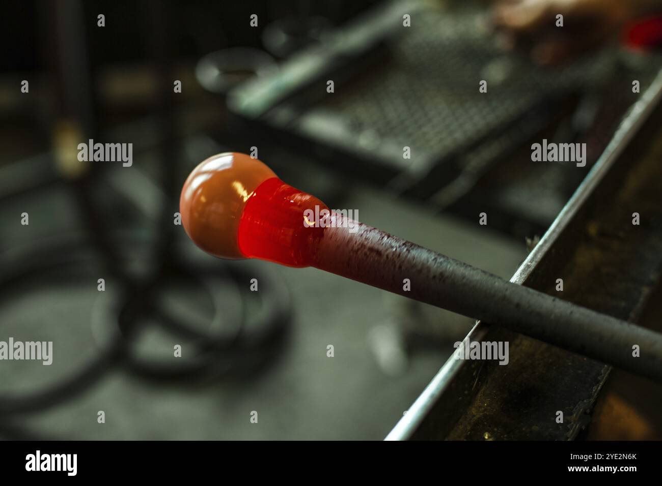 Man is starting a glass blowing project to create an ocher colored ...