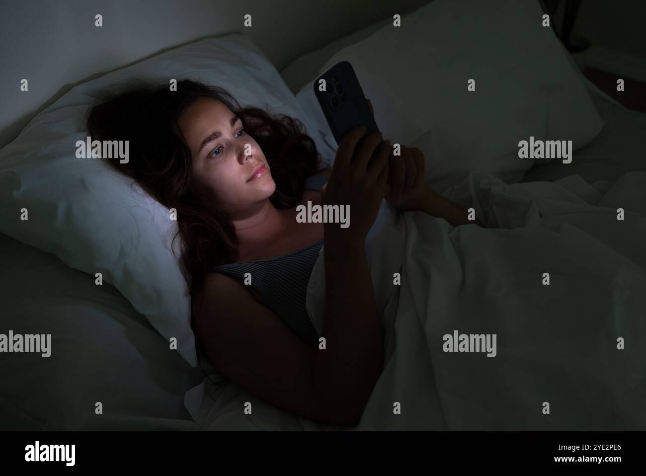 woman, in the dark in bed, staring her phone glow. insomnia and smartphone addiction Stock Photo ...