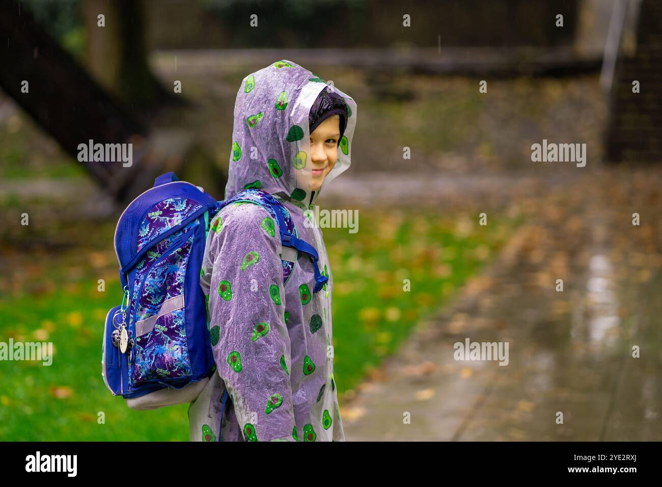 A child in a raincoat with a school bag goes to school in the rain ...