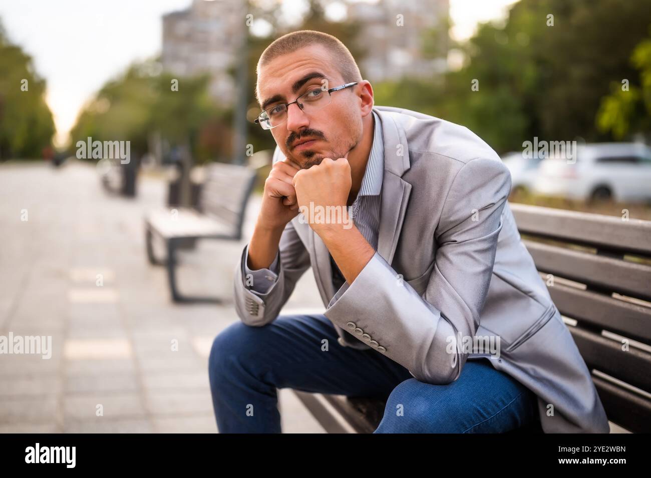 Portrait of thoughtful and worried man. He is sitting on bench in the ...