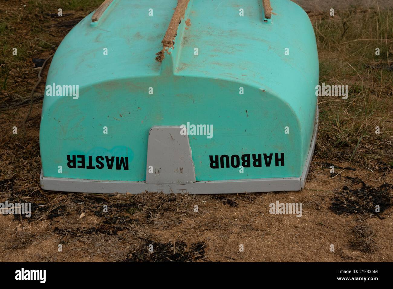 Upside down turquoise green hull of a small rowing boat with the name ...