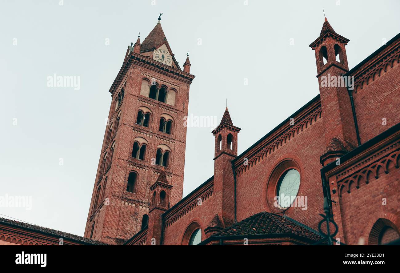 The impressive brick bell tower stands tall against a pale sky in Alba ...