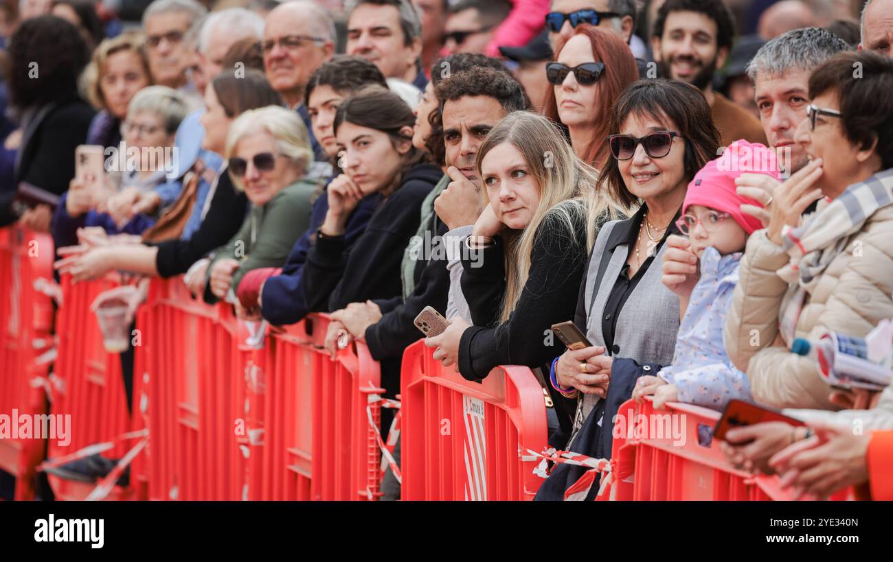 A diverse group of spectators gathers behind barriers, immersed in ...
