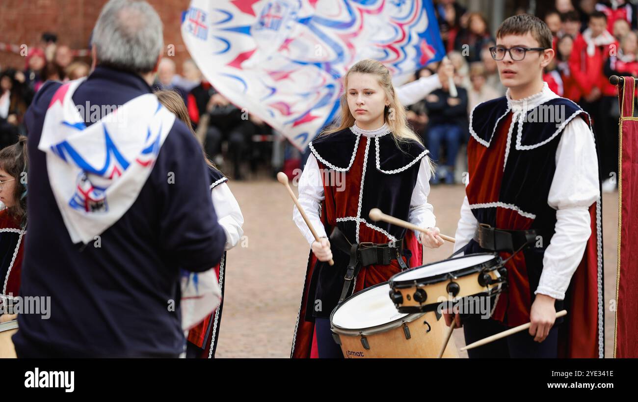 Young performers in traditional attire drum and twirl flags during a ...
