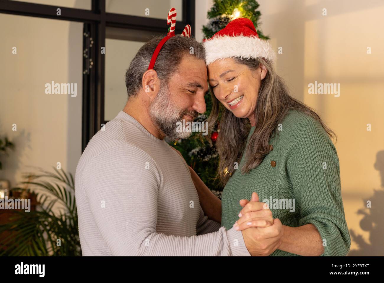 Dancing joyfully at home, mature couple celebrating Christmas together ...
