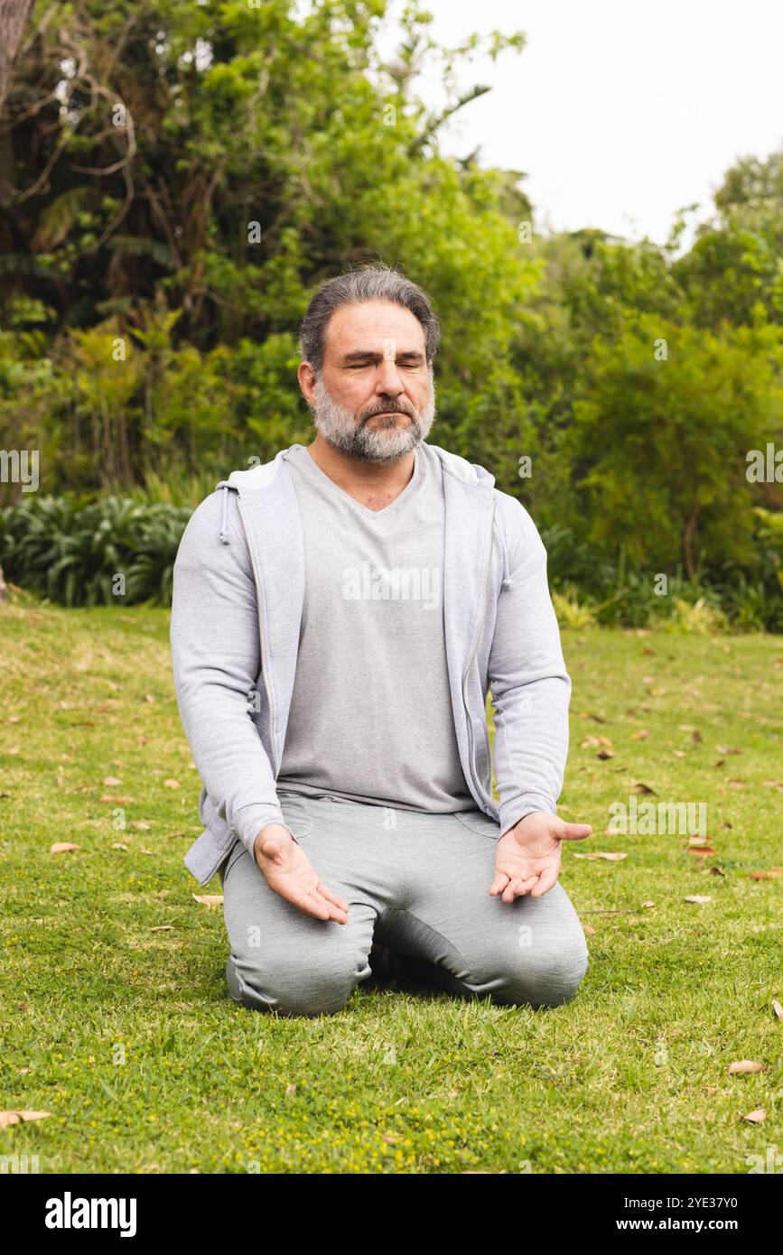 Mature man meditating outdoors on grass, finding peace and relaxation ...