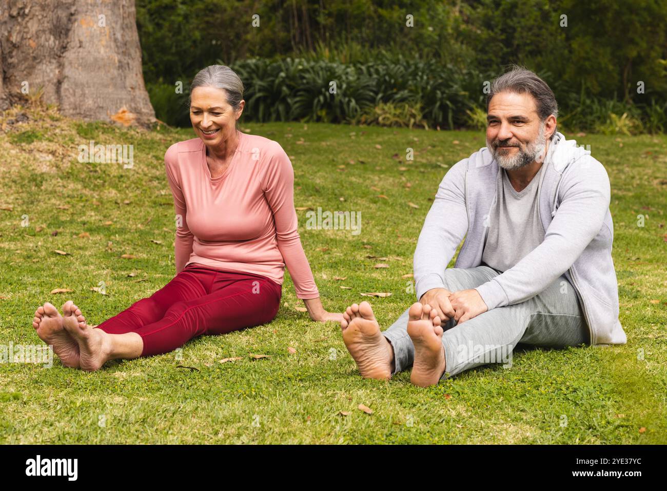 Mature couple stretching on grass, enjoying outdoor exercise and ...