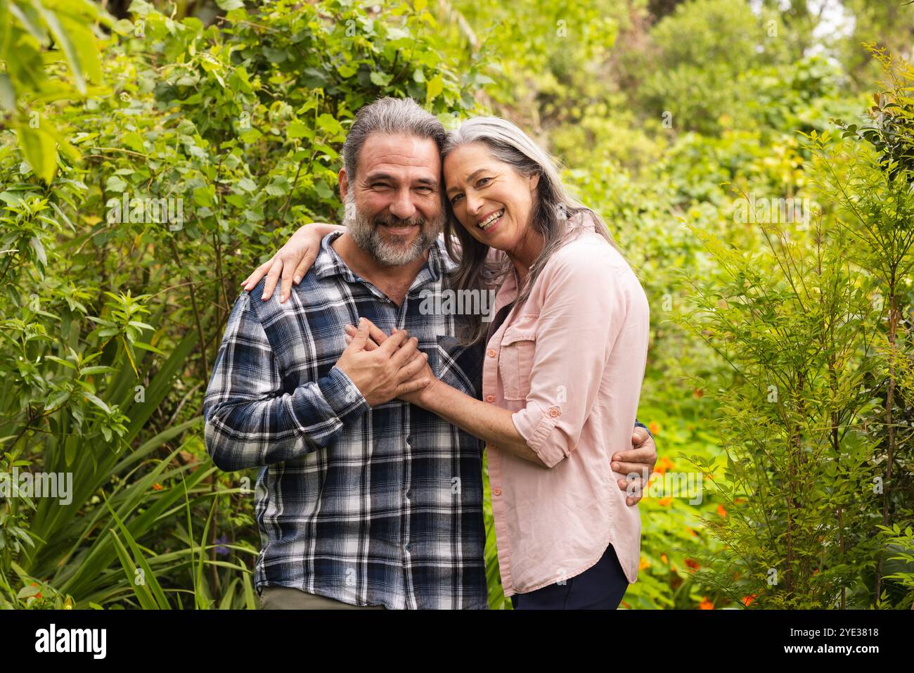 Happy mature couple embracing in lush garden, enjoying nature together ...
