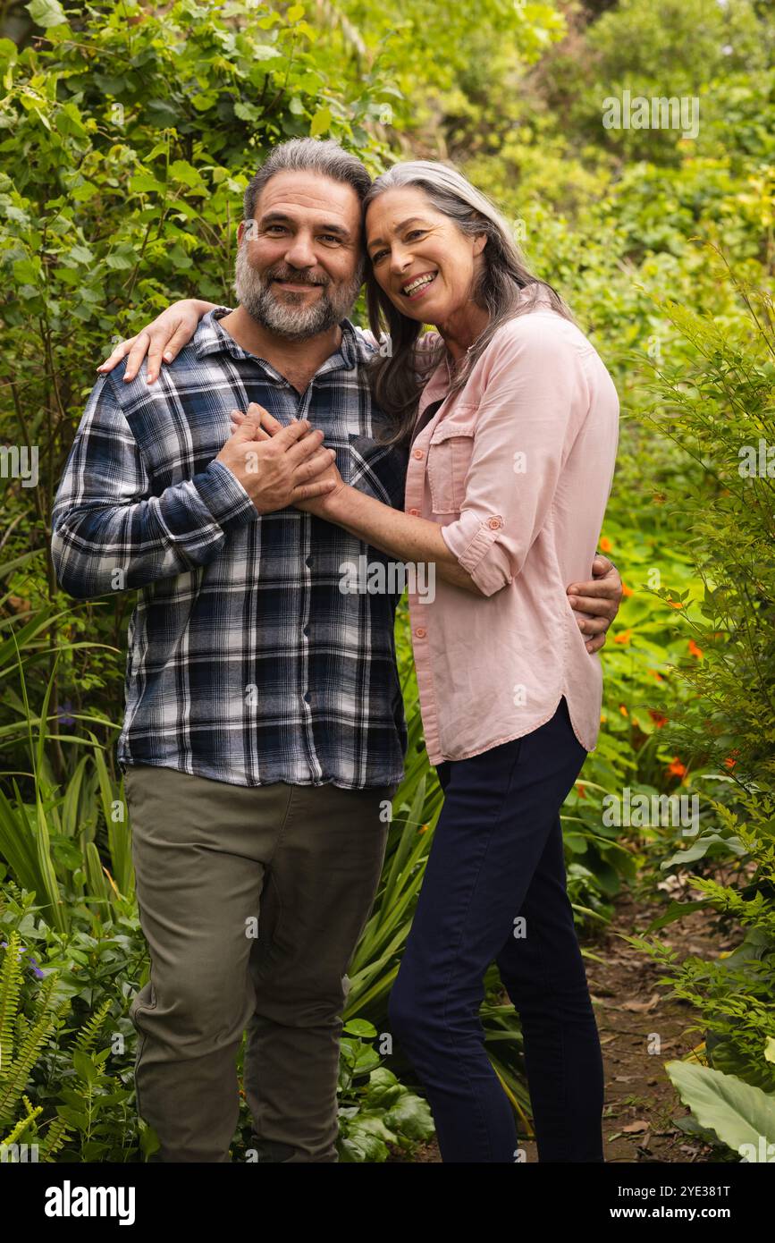Happy mature couple embracing in lush garden, enjoying nature together ...