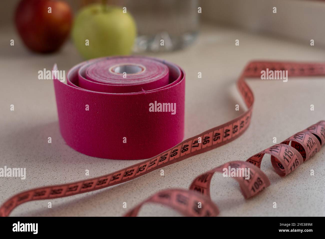 Pink kinesio tape with a measuring tape lying on a white background ...