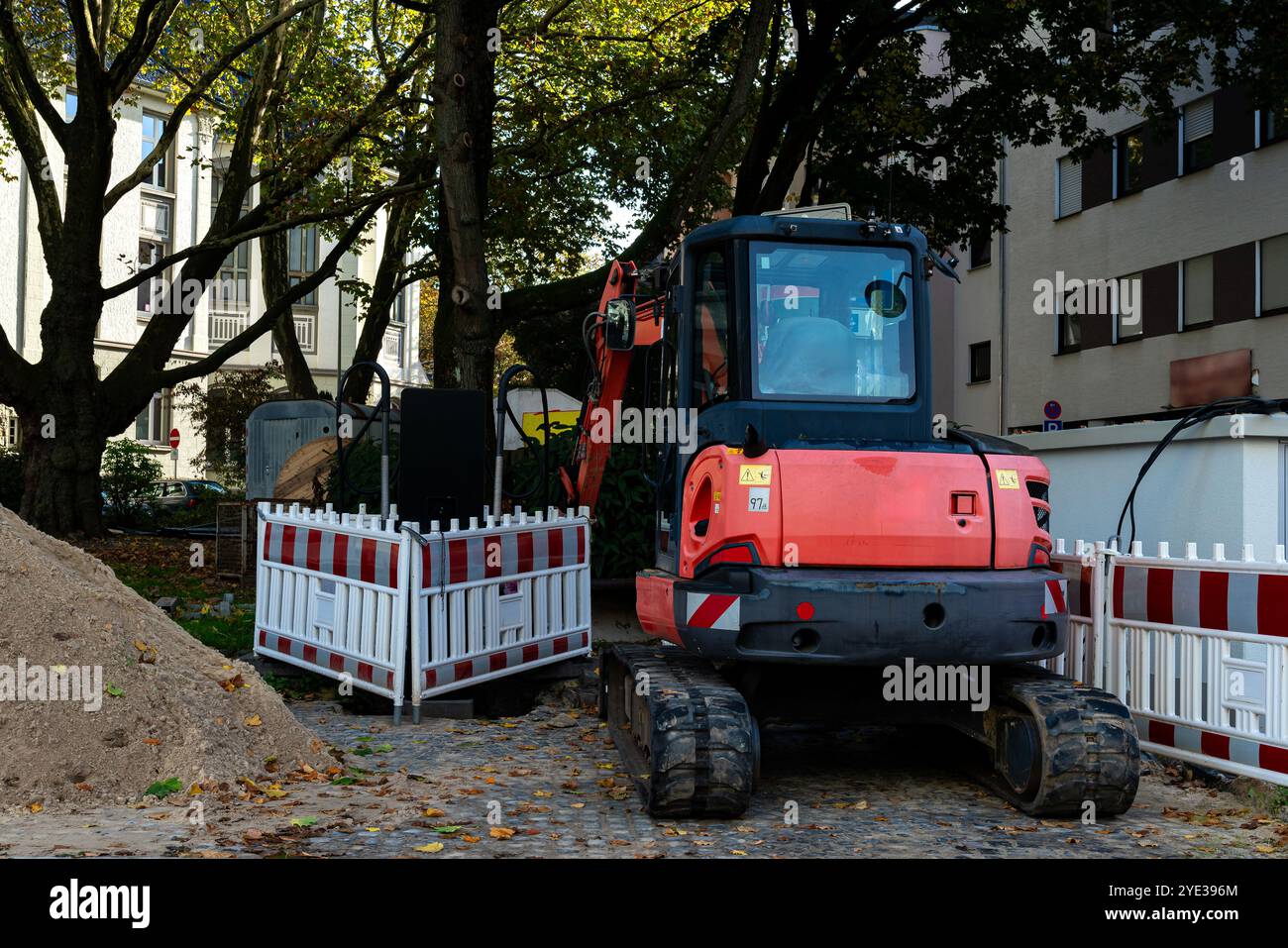 An excavator is operating on a city street, digging near a construction ...