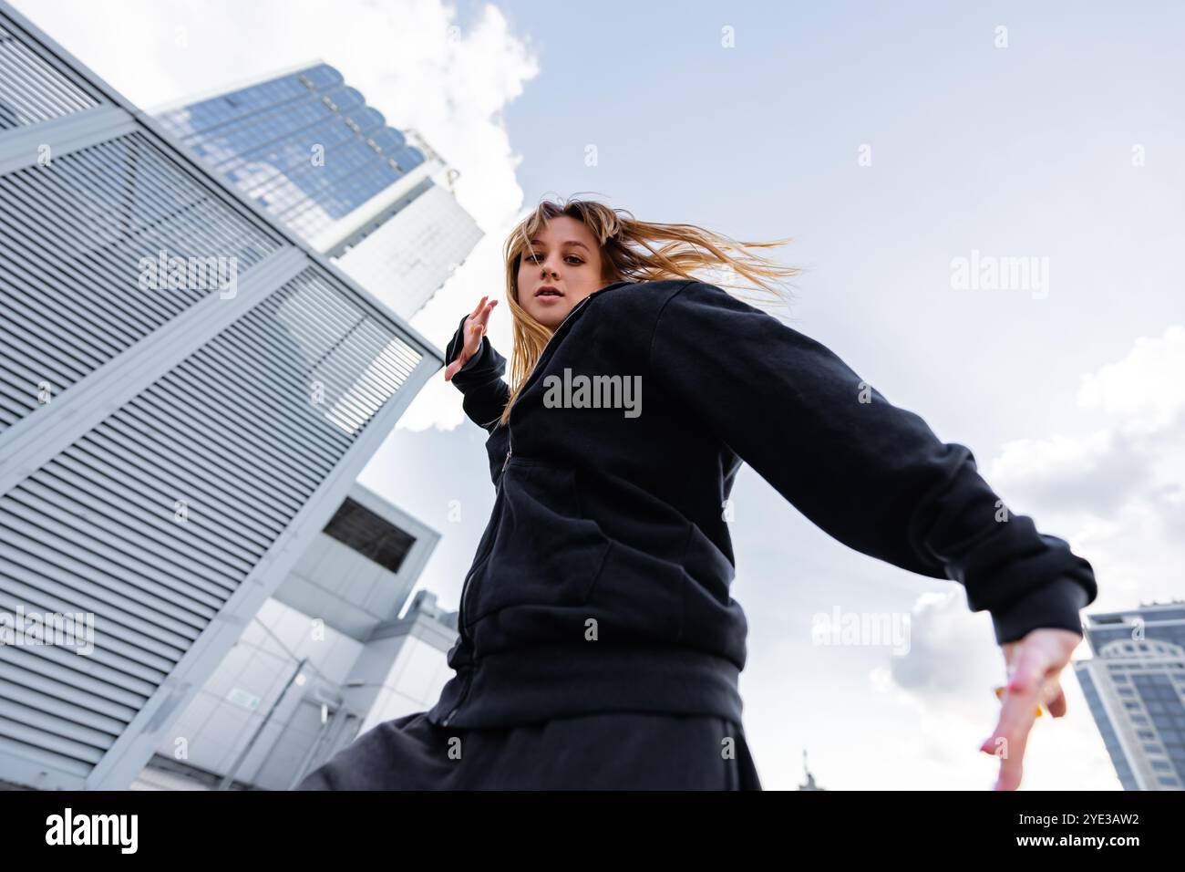Dynamic urban dancer performing expressive movements on a city rooftop ...