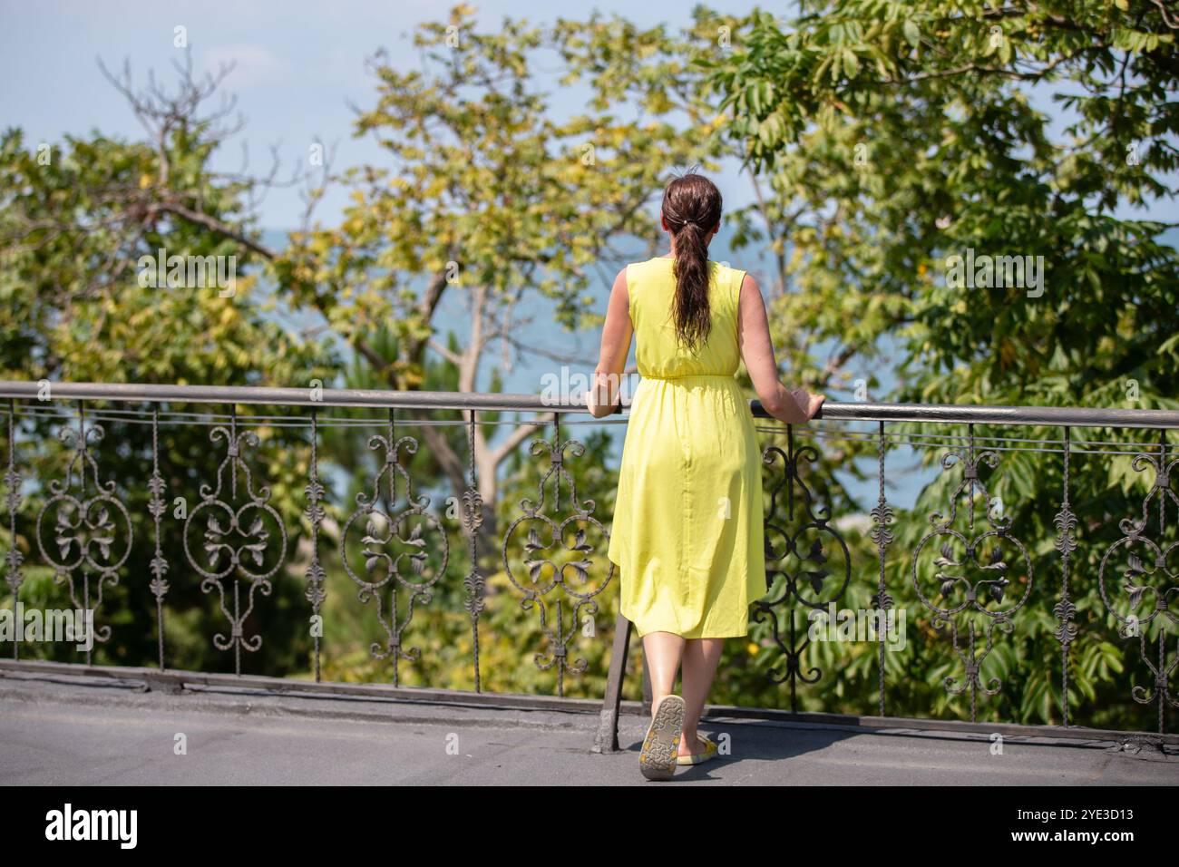 A woman looks out from the balcony terrace through the greenery. Admire ...