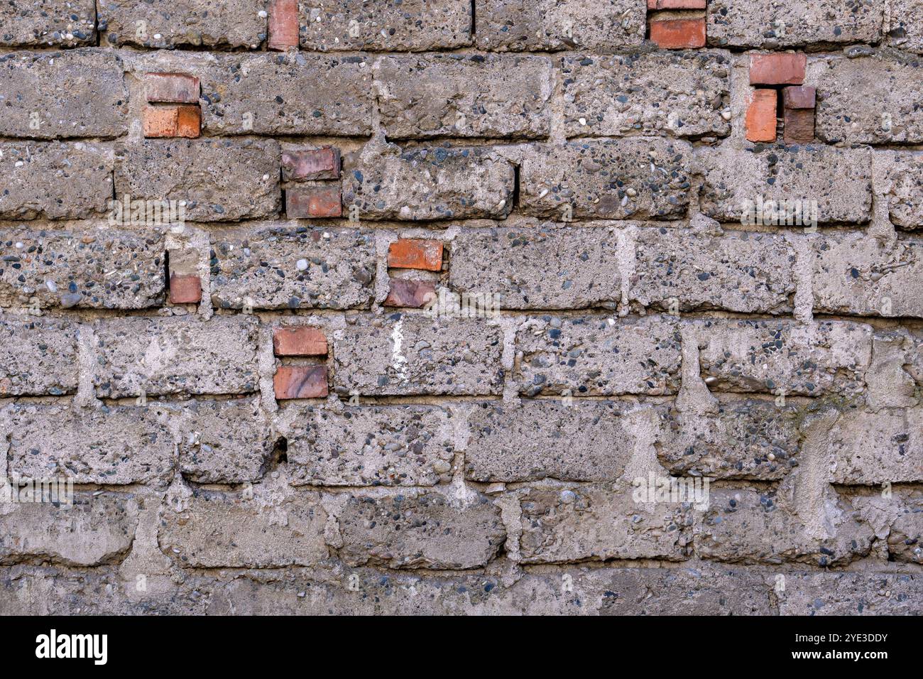 A brick wall with a few bricks missing. The wall is grey and has a ...