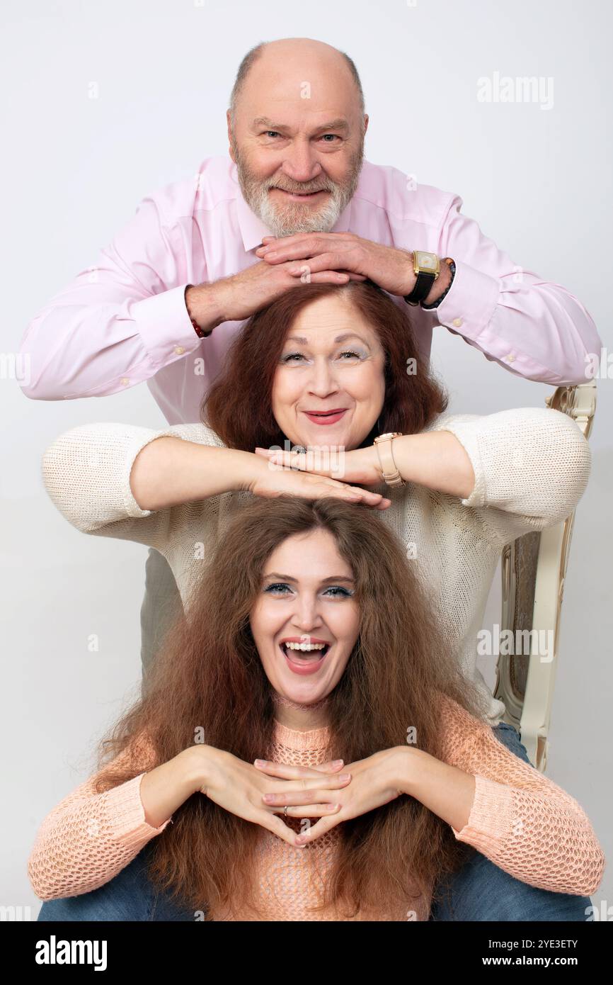 A creative family portrait of elderly parents and an adult daughter on a gray background Stock ...