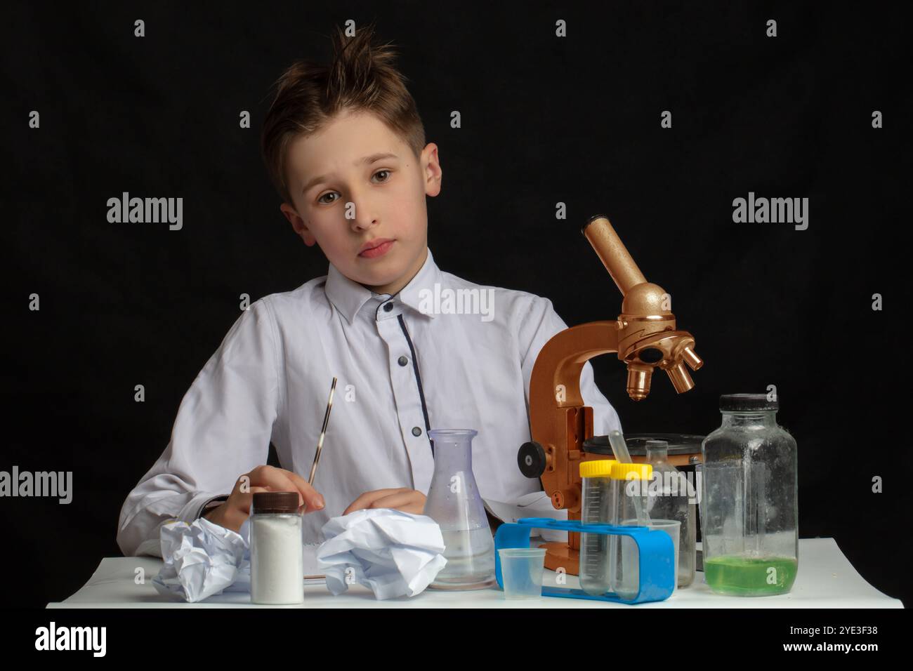 A boy scientist researcher with a microscope conducts experiments in ...