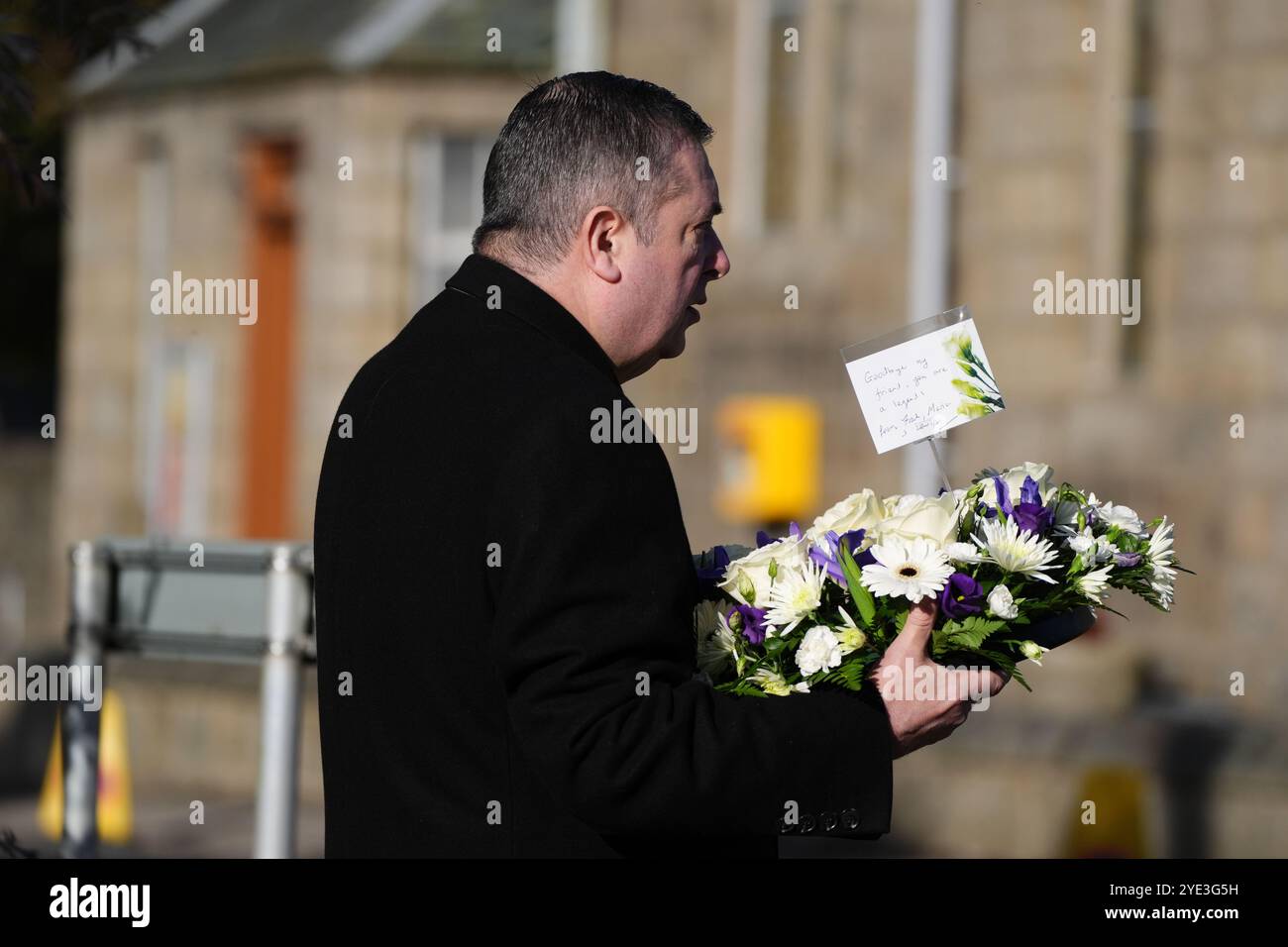 Lord Frank Mulholland carries a wreath as he arrives for the funeral ...