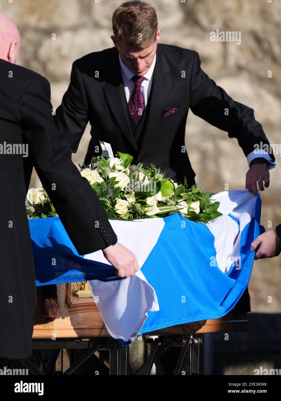 Pall bearers drape a Saltire flag over the coffin as it arrives at the ...