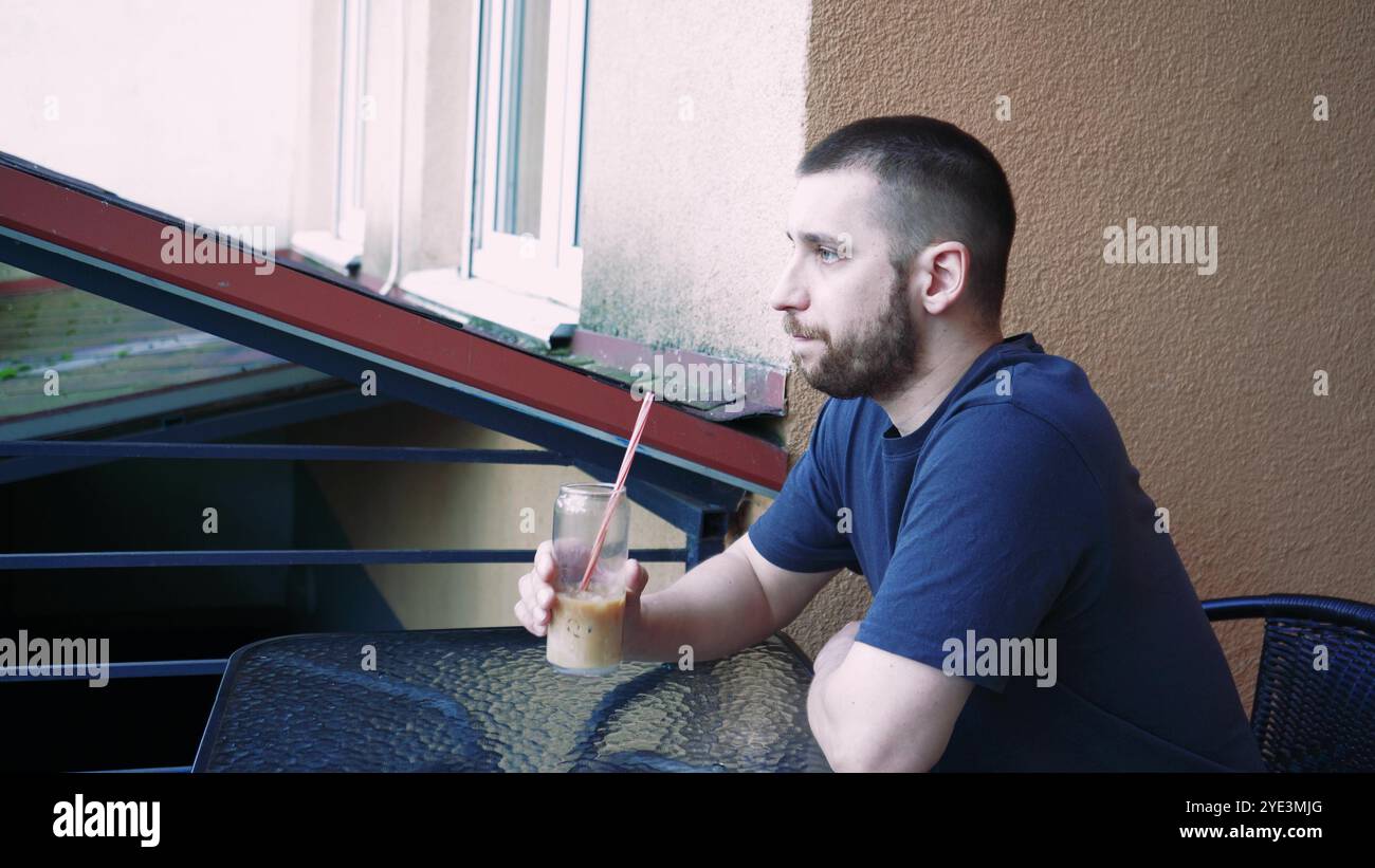 Captured in a moment of tranquility, a man relaxes alone with his drink ...