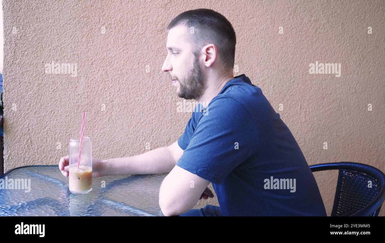 Captured in a moment of tranquility, a man relaxes alone with his drink ...