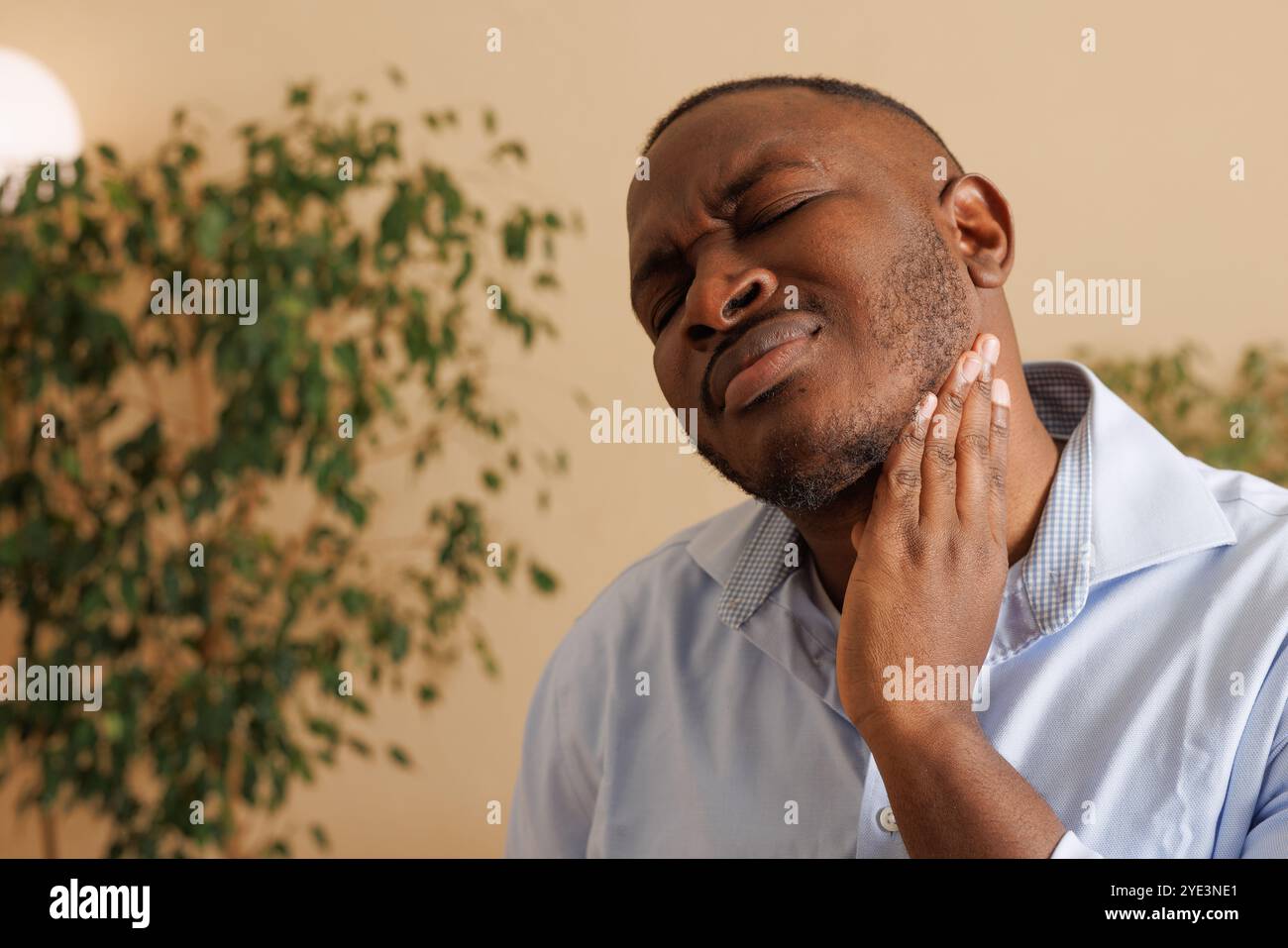 Man sitting on sofa in living room and feeling pain in neck and throat ...