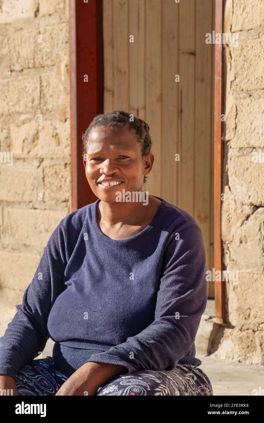 african woman in the village sitting on the veranda porch in front of ...