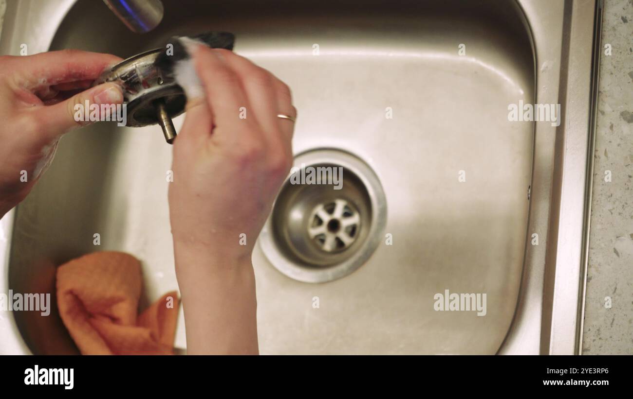 Hands wipe metal part and kitchen sink. The scene reflects the essence ...