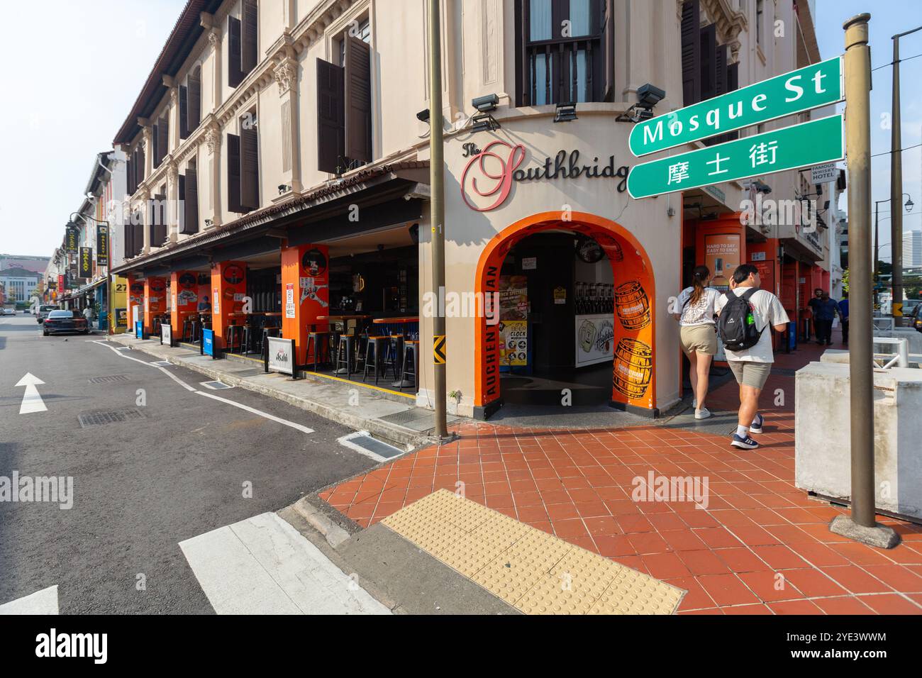 People walk pass road sign name, Mosque Street. Long stretch of ...