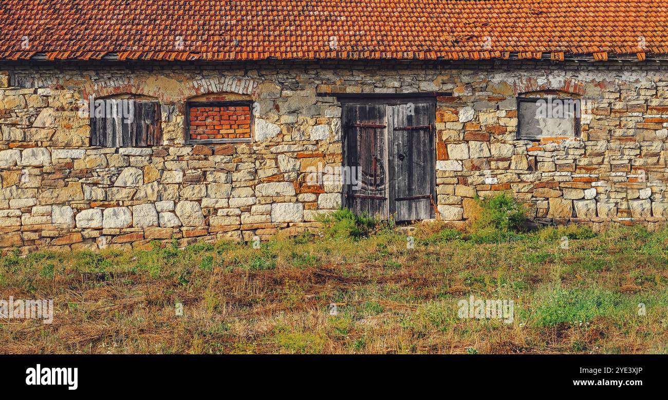 Rustic stone shed with aged wooden doors, red tiled roof, vintage ...
