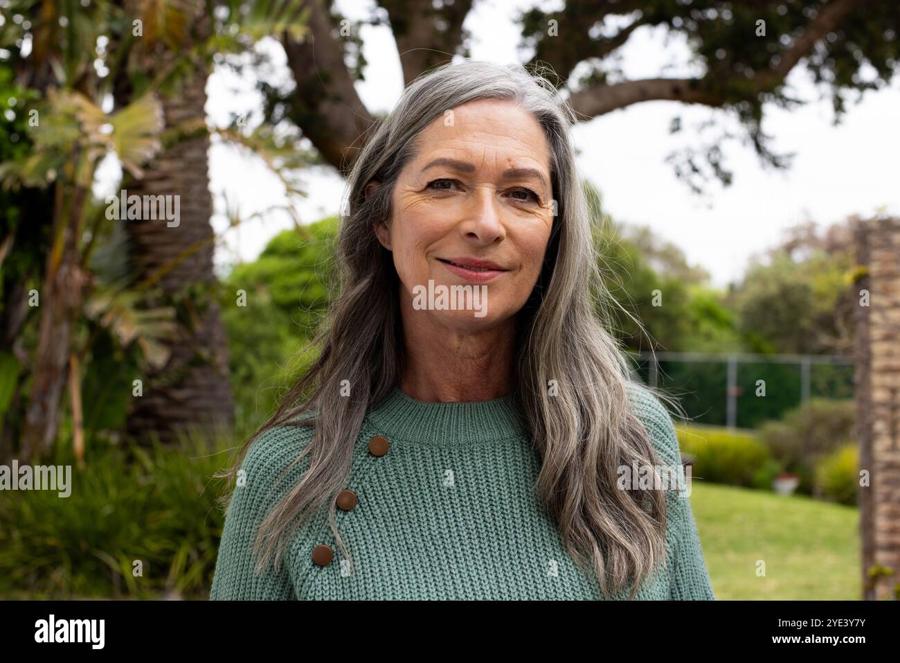 Smiling mature woman enjoying peaceful outdoor moment in lush garden ...
