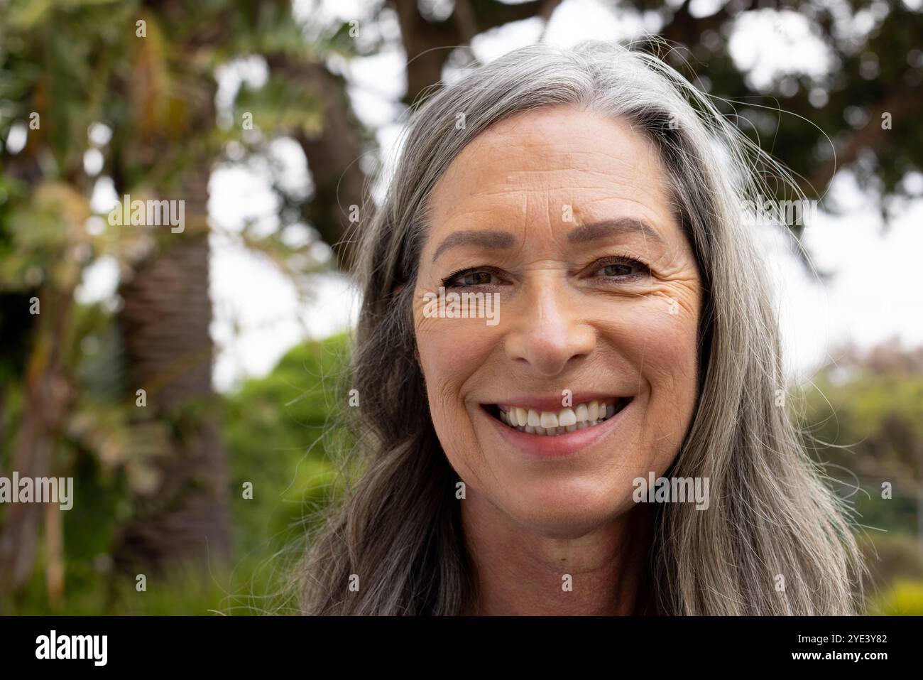 Smiling mature woman enjoying nature outdoors, radiating happiness and ...