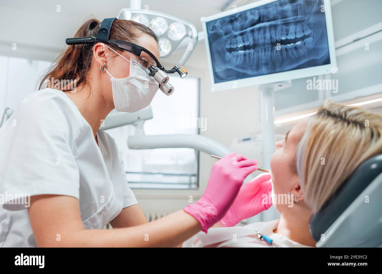Dentist female doctor dressed uniform in magnifying glasses performing ...