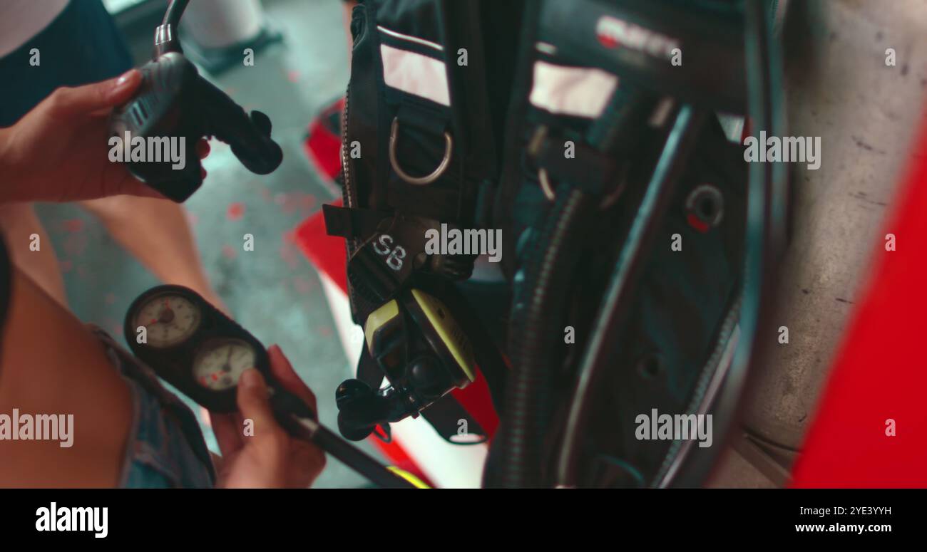 Diver is preparing scuba diving equipment and checking the oxygen gauge ...