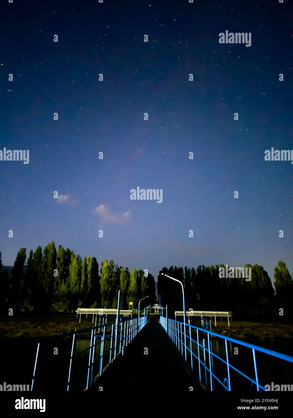 A long pier under a starry sky, leading into the darkness of the lake ...