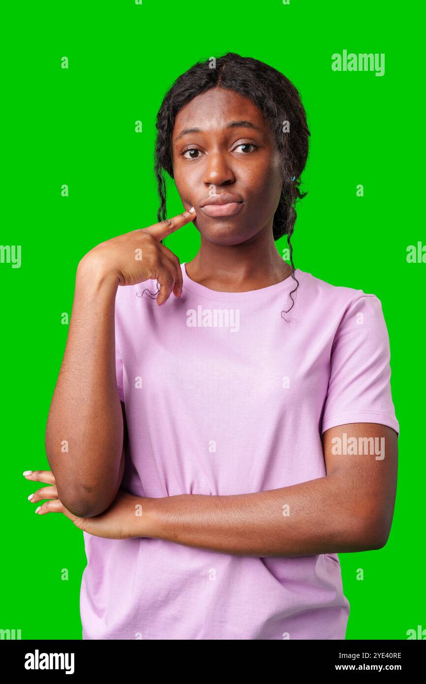 Thoughtful woman pondering in front of a bright green background during ...