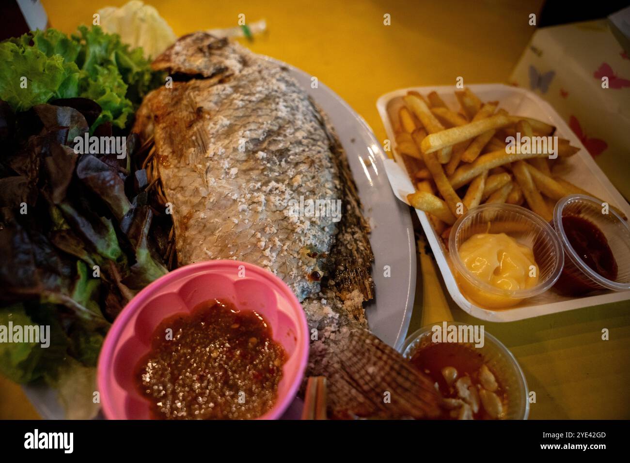 Grilled salt-crusted tilapia with fries and dipping sauces at the ...