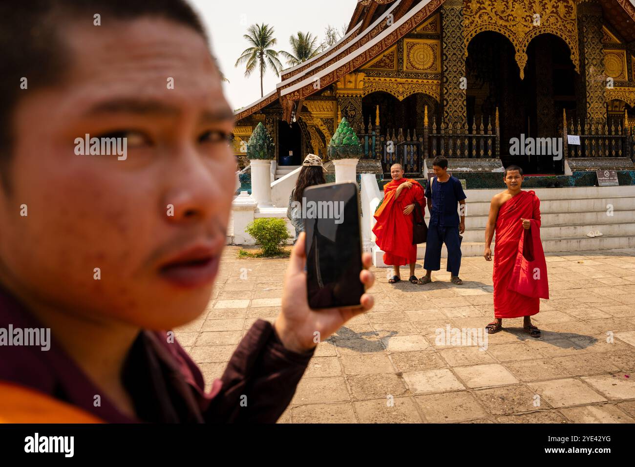 Temple scene in Luang Prabang, Laos, with monks and visitors captured ...